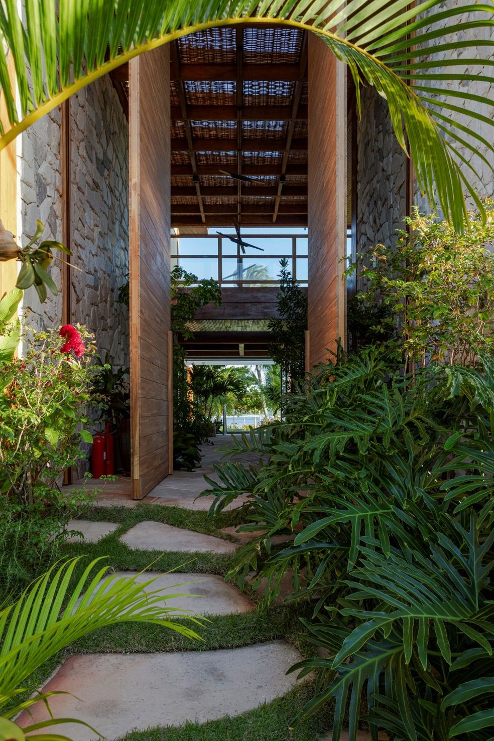 Casa à beira-mar combina grandes vãos, madeira e paisagismo exuberante